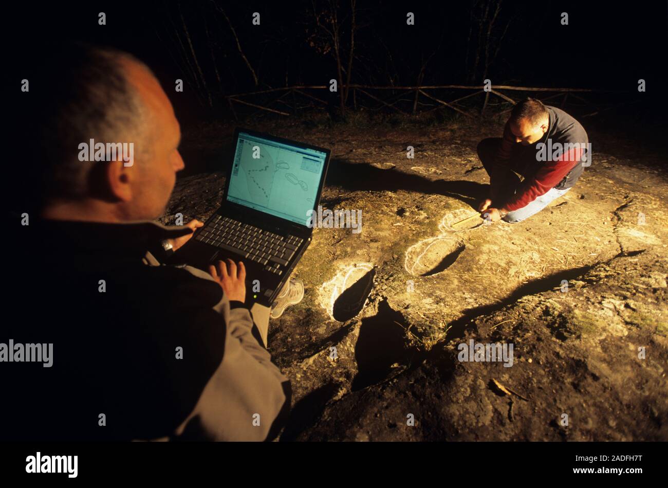Early human footprints. Researchers working by floodlight on fossilized ...