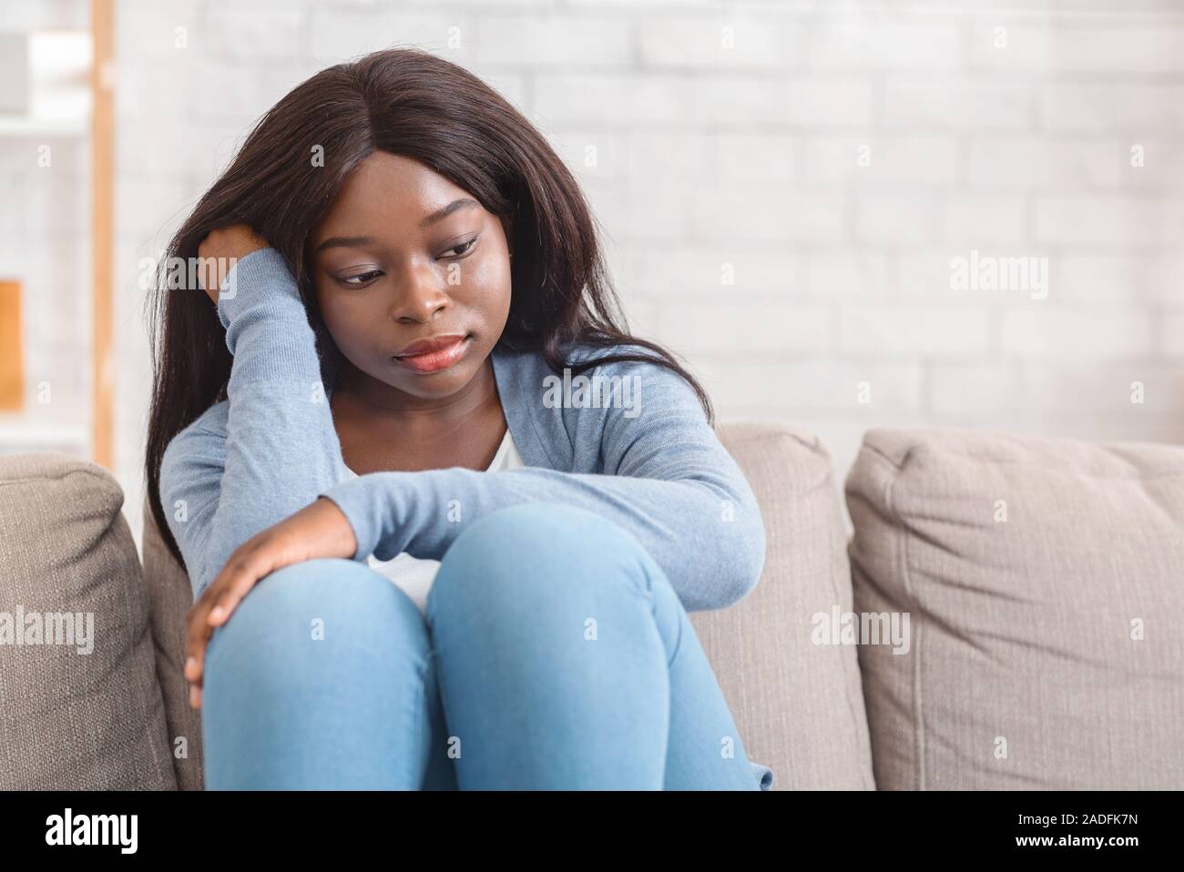 Portrait of sad black woman sitting on couch at home Stock Photo - Alamy