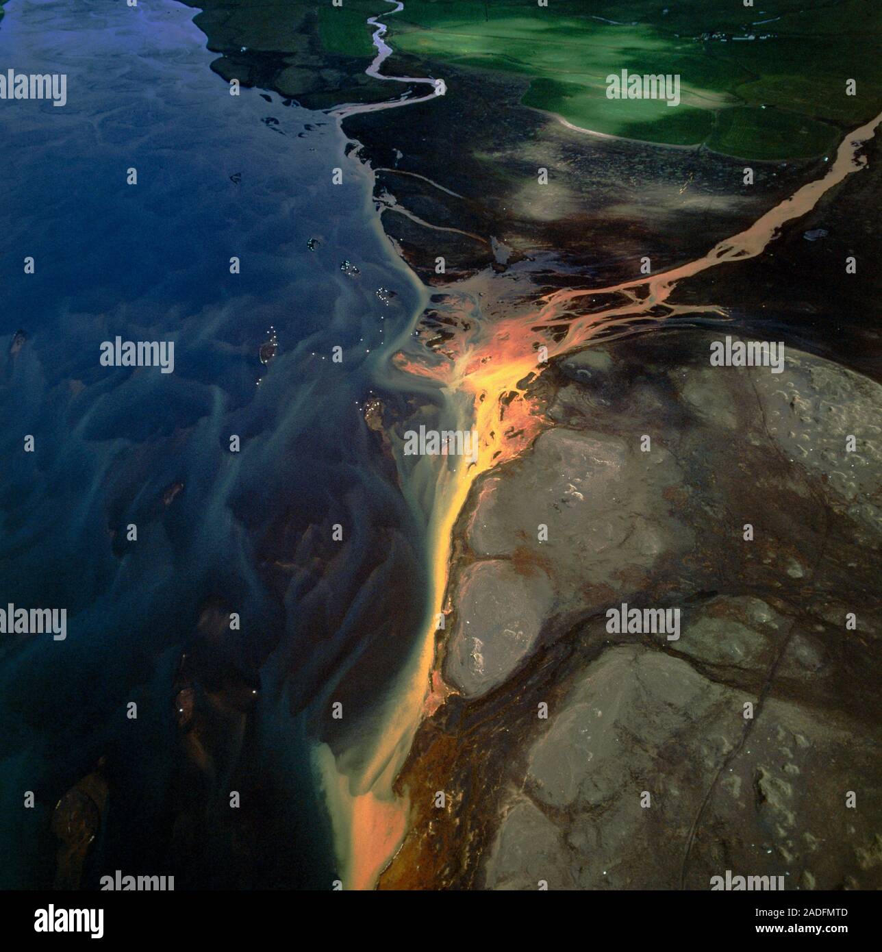 Iron-rich river. Aerial view of a bright orange tributary running into ...