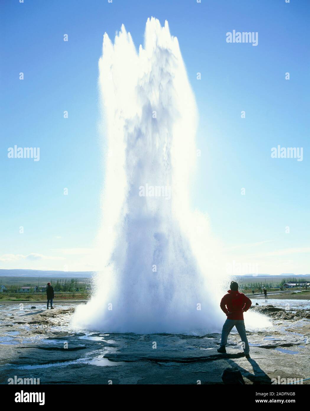 Geyser erupting next to tourists. A geyser is a deep natural well in a ...
