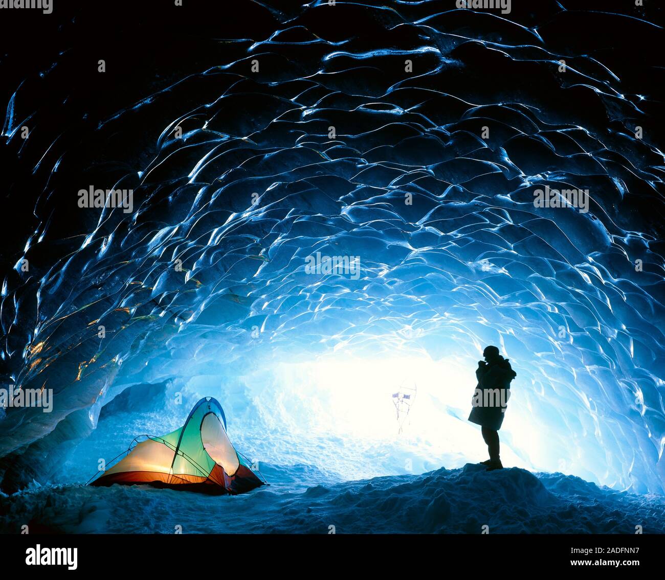 Ice cave interior. Explorer with a tent in an ice cave. Such caves are ...