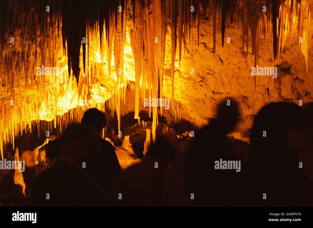 Stalactites hanging from the roof of a limestone cave, with silhouetted ...