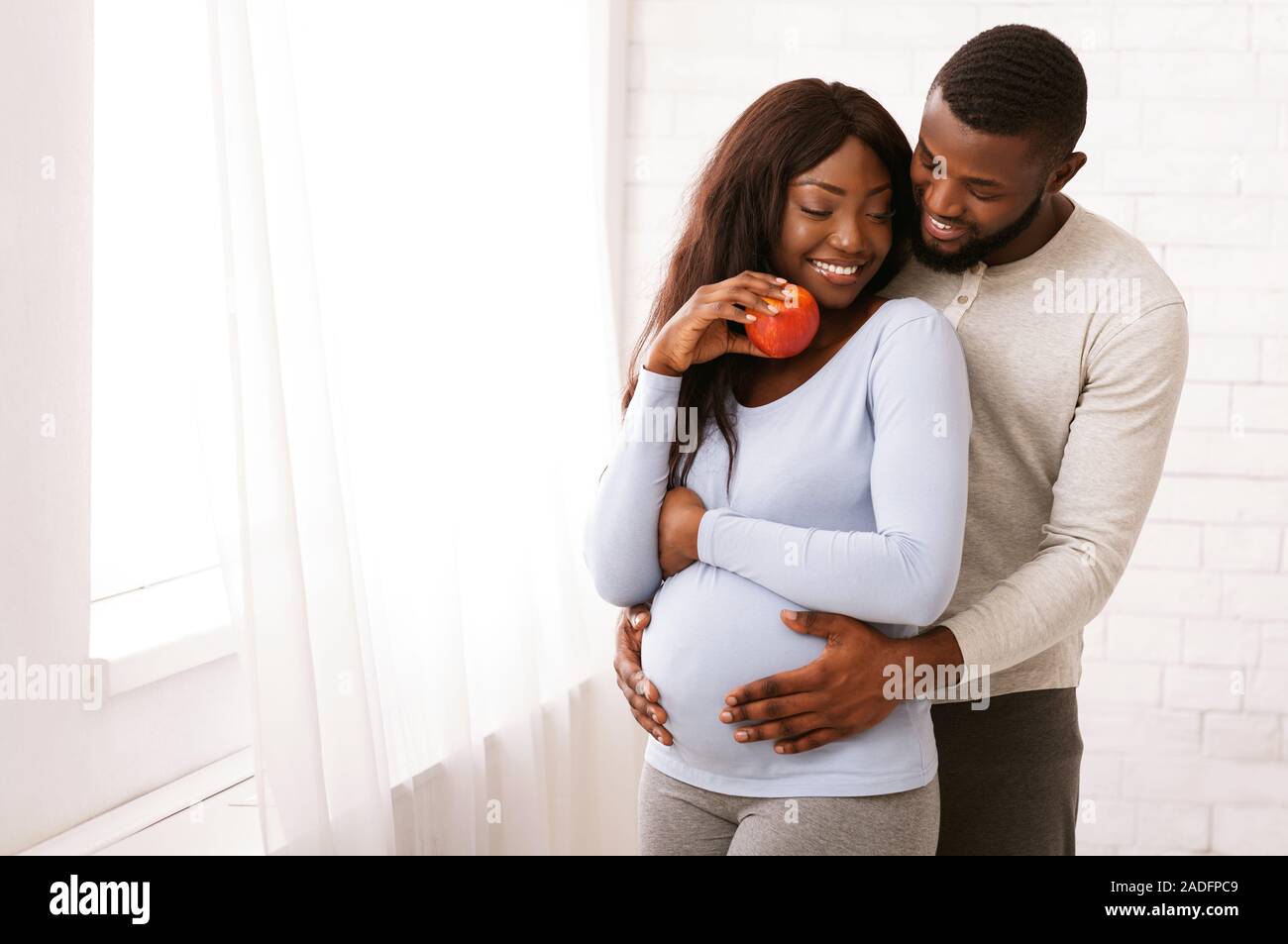 Lovely black couple cuddling at home next to window Stock Photo - Alamy