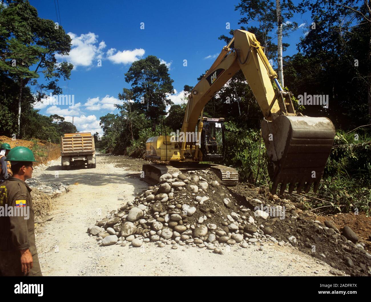 Road construction. Digger digging at the side of a road being built ...