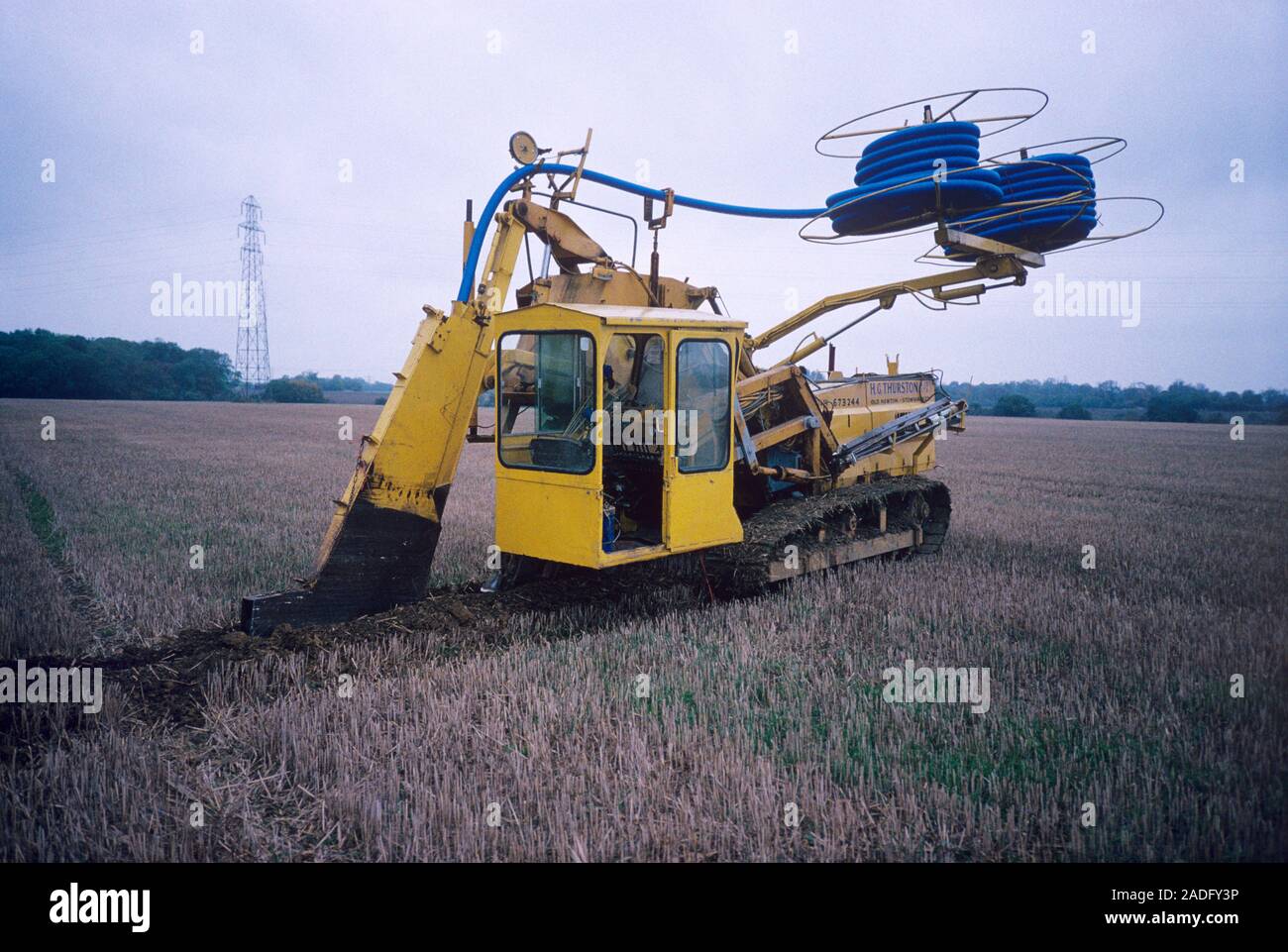 Machine digging a trench and laying drainage pipe Stock Photo - Alamy