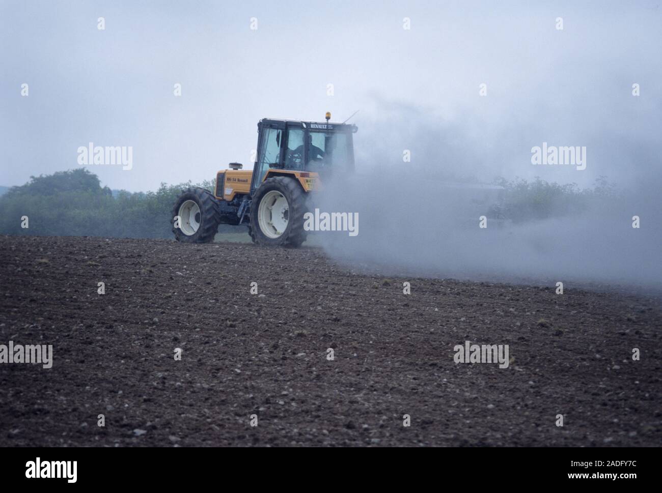 Spreading fertiliser. Tractor spreading fertiliser on a ploughed field ...