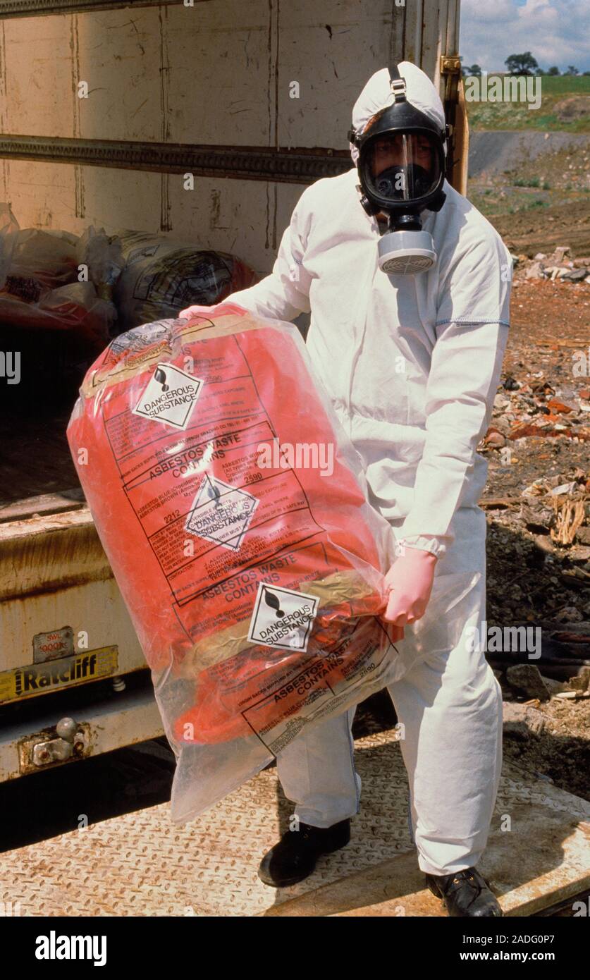 Worker wearing a protective suit & breathing mask unloading sacks of ...