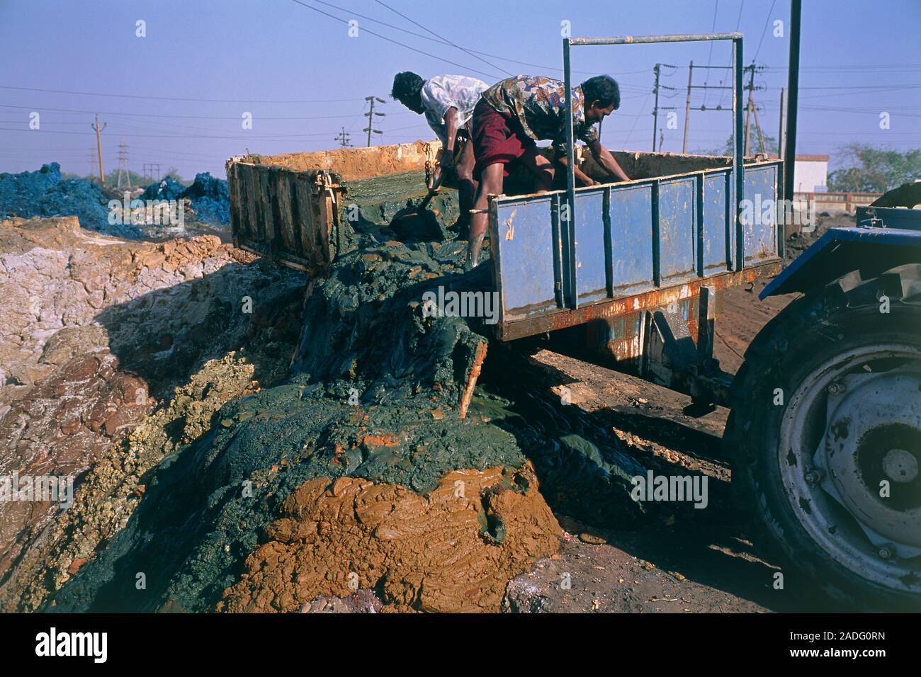 Chemical waste dump. Asian workers unload chemical waste from a trailer ...