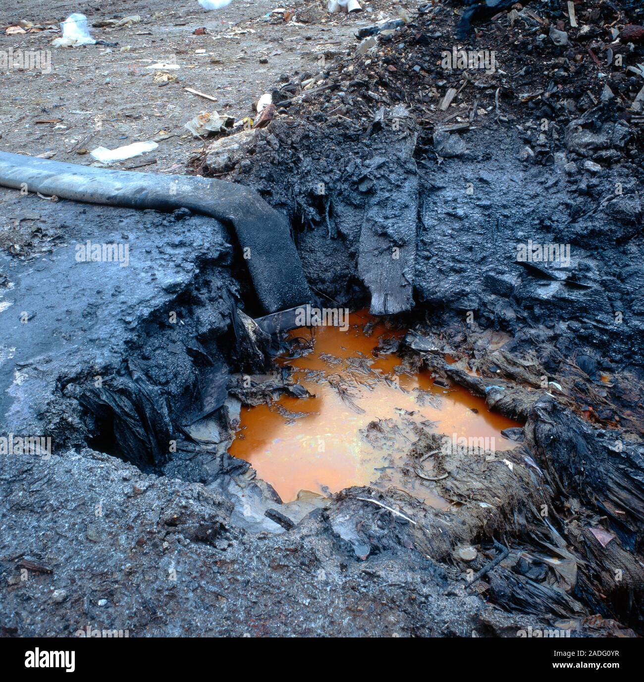 Toxic waste dump. Discharge pipe (left) leading into a pool of toxic ...