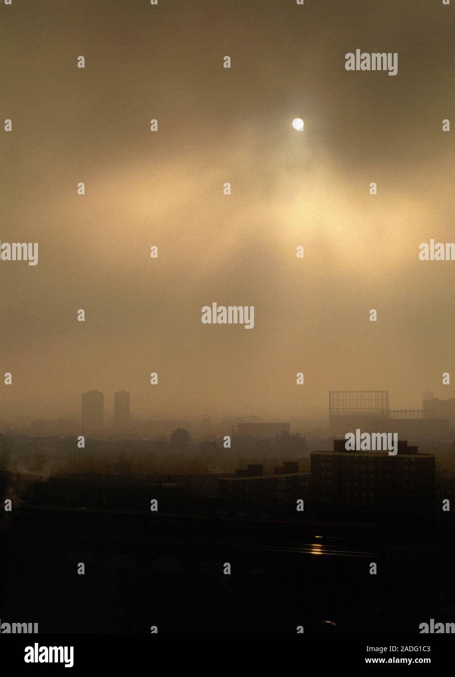 Air pollution. Sun obscured by a haze of air pollution over a city ...