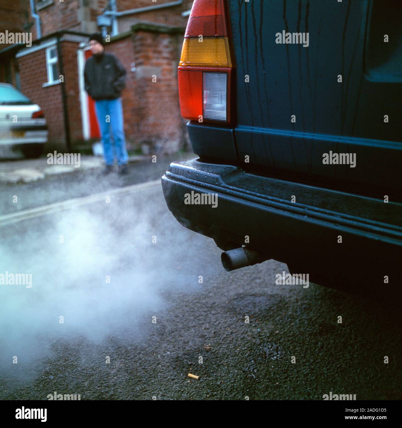 Traffic pollution. Car exhaust fumes in an urban area with a pedestrian ...