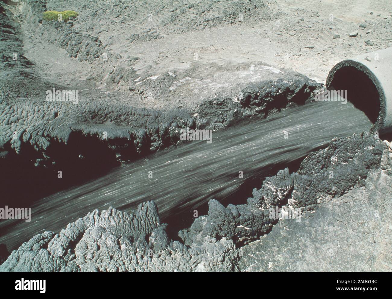 Mining pollution. Sludge flowing from a pipe. Water has been used to ...