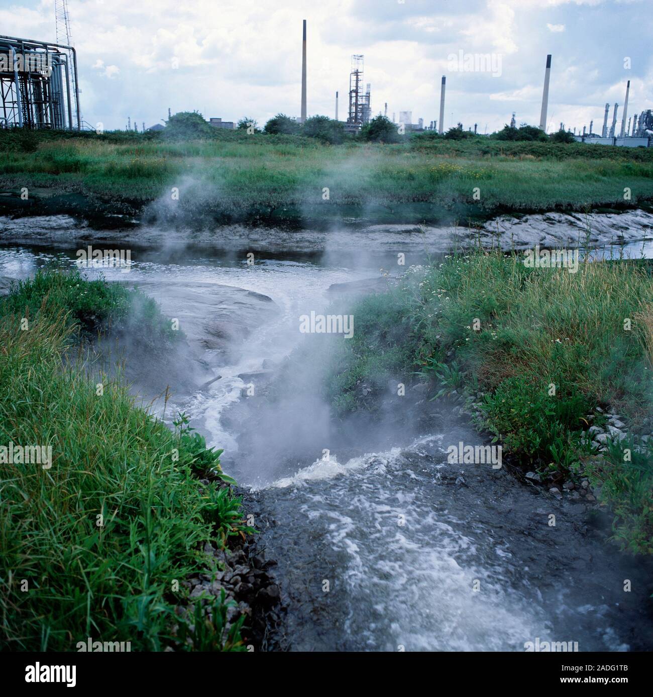 Water pollution. Hot effluent from an oil refinery flowing into a river ...