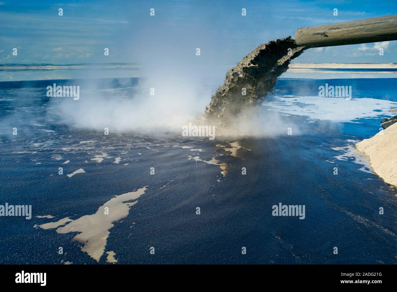 Oil industry pollution. Tailings outflow pipe pumping a mixture of hot ...