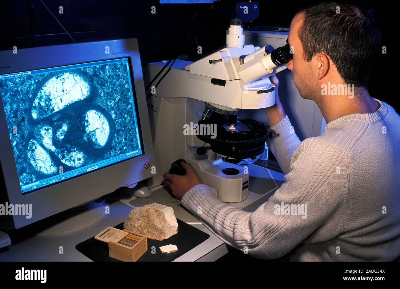 Archaeological research. Researcher examining a sample of rock through ...