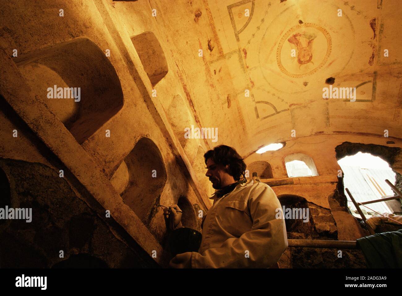 Roman burial house. Restorer cleaning a burial niche inside a Roman ...
