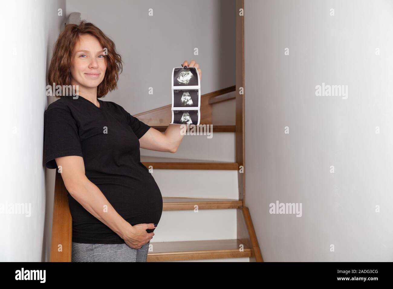 Pregnant curly woman looking at her baby sonography. Happy expectant ...