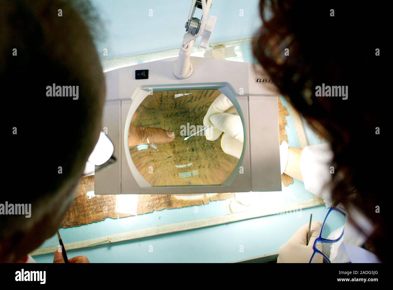 Egyptian papyrus conservation. Magnifying glass being used to study the ...