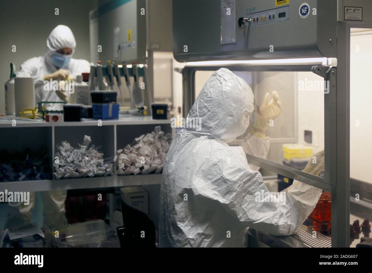 Gene therapy research. Researchers in protective suits handling HIV ...
