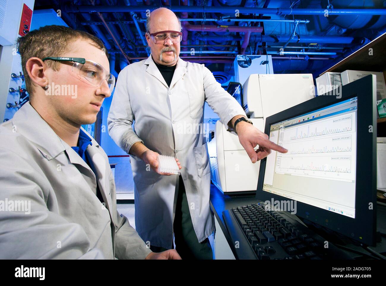 DNA research. Geneticist (centre) and technician (left) analysing DNA ...