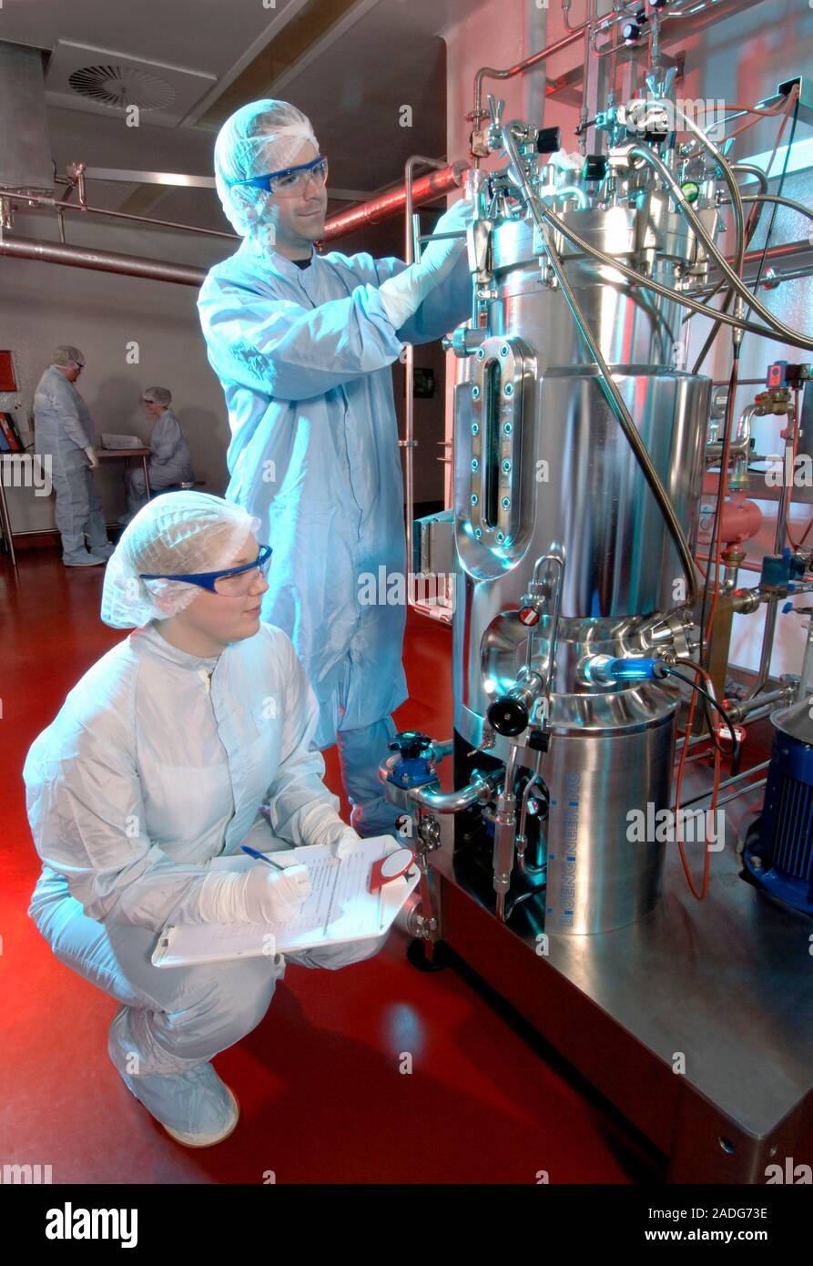 Microbial fermentation. Workers in clean room suits inspecting a ...