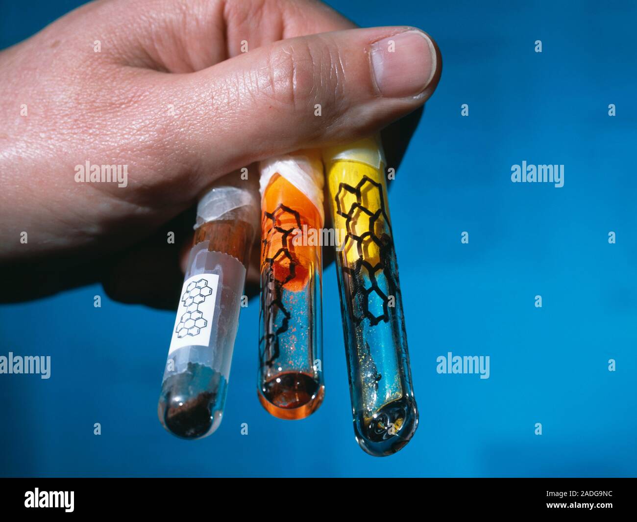 Astrochemistry products. Hand holding test tubes containing polycyclic ...