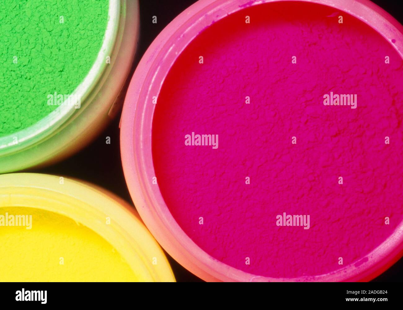 Coloured powder. Overhead view of three jars of coloured, synthetic ...