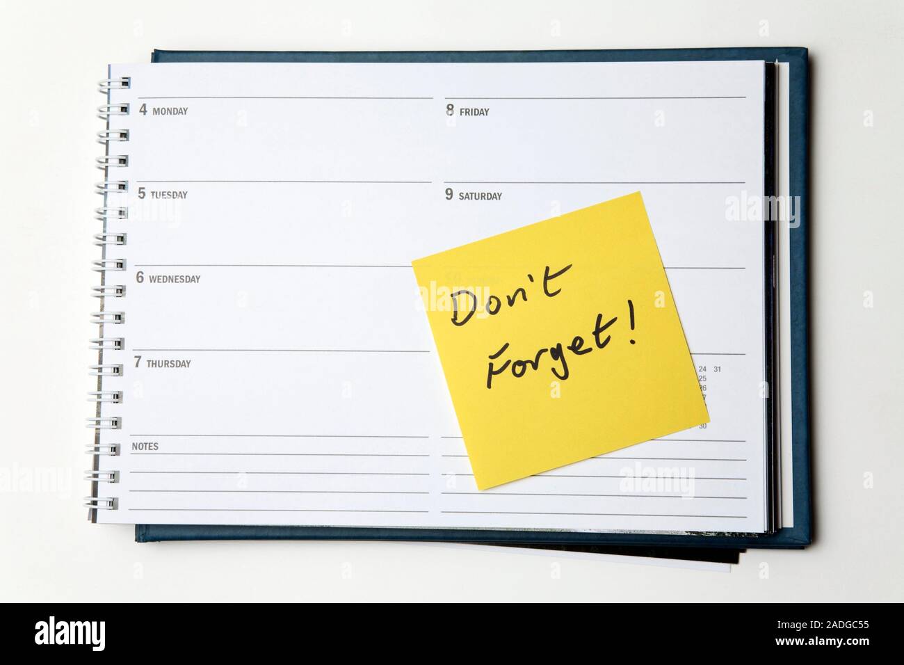 Diary reminder. Post-it note placed on a diary to remind the diary ...