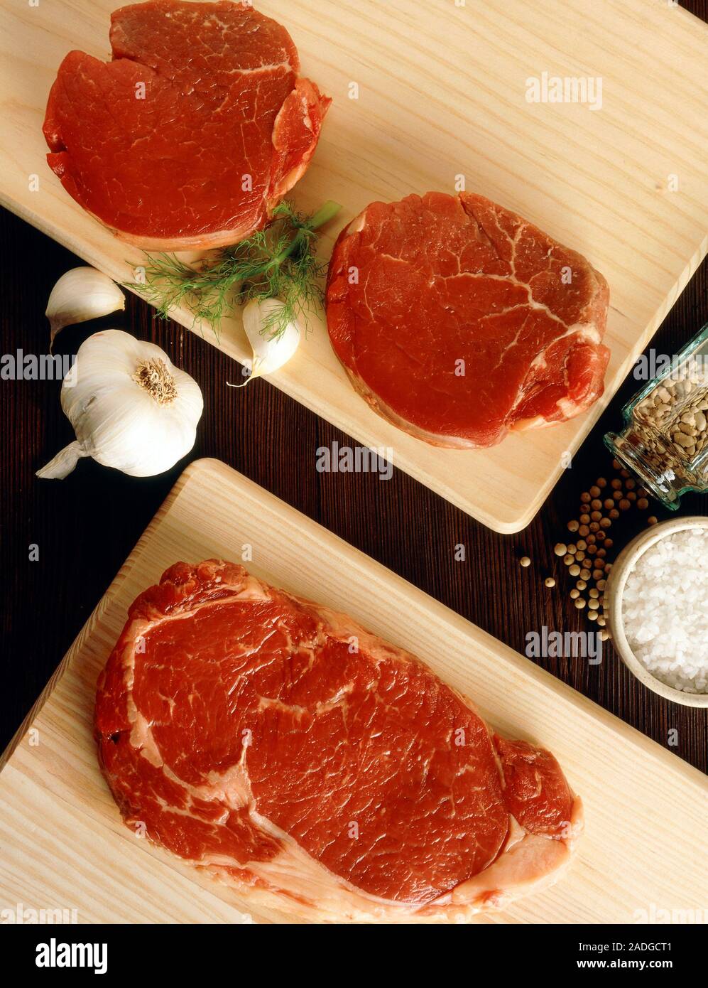Beef. Raw beef joints and a beef steak on chopping boards with garlic ...