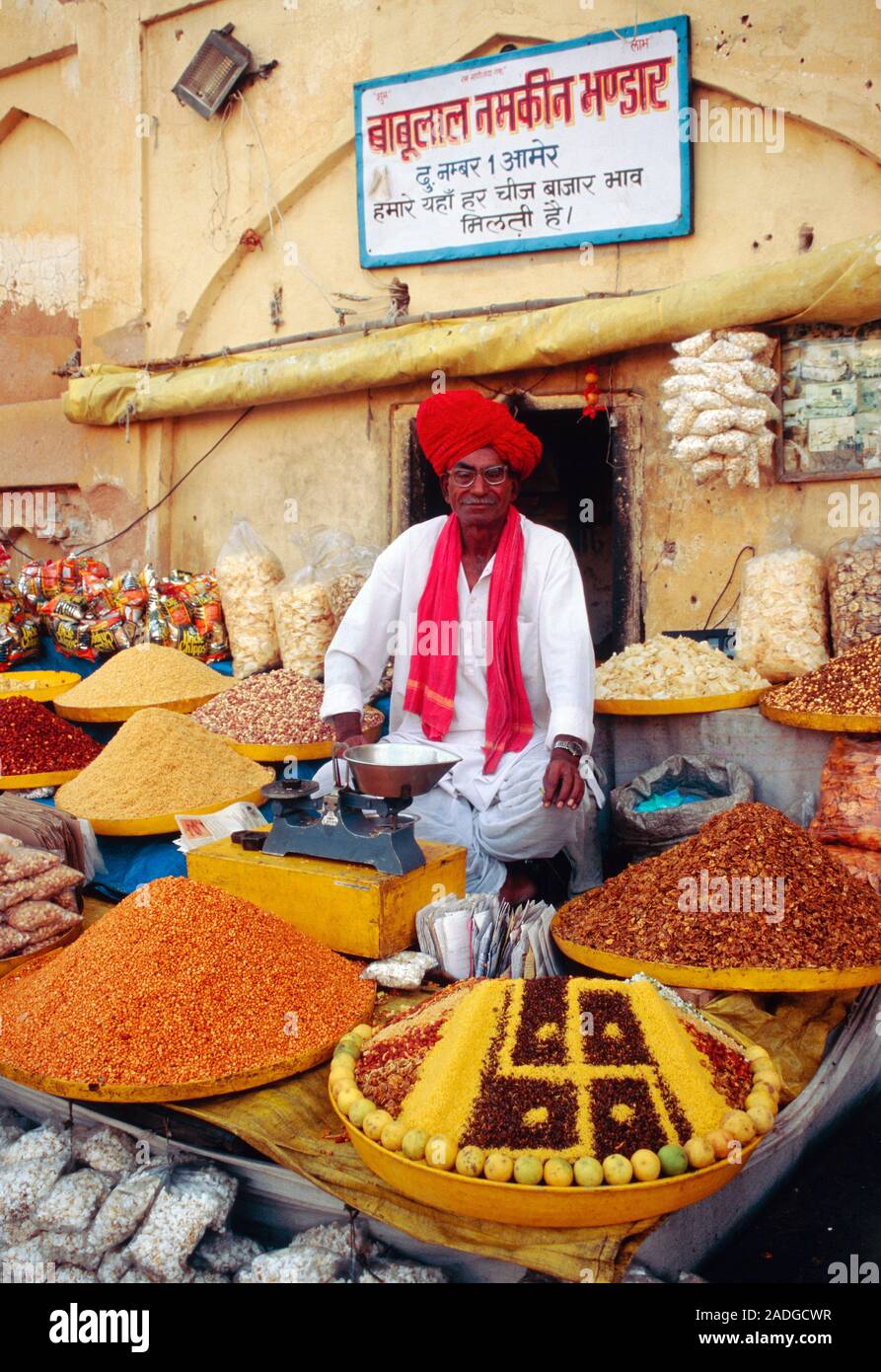 Spice seller. View of an Indian spice seller sitting amongst baskets of ...