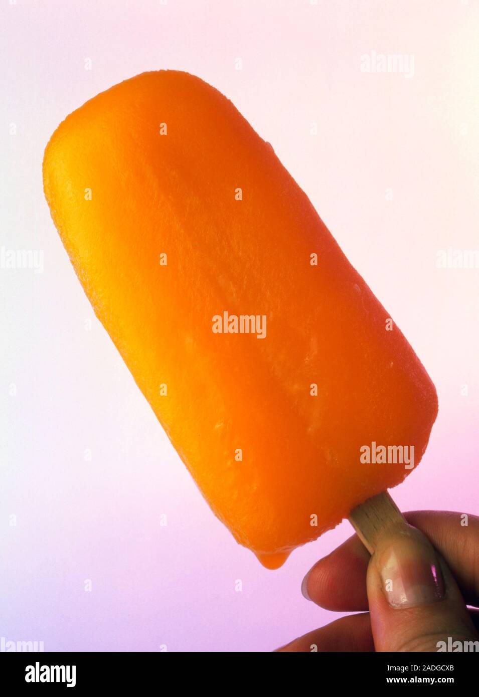 Ice lolly. View of a hand holding a melting ice lolly (lollipop). This ...