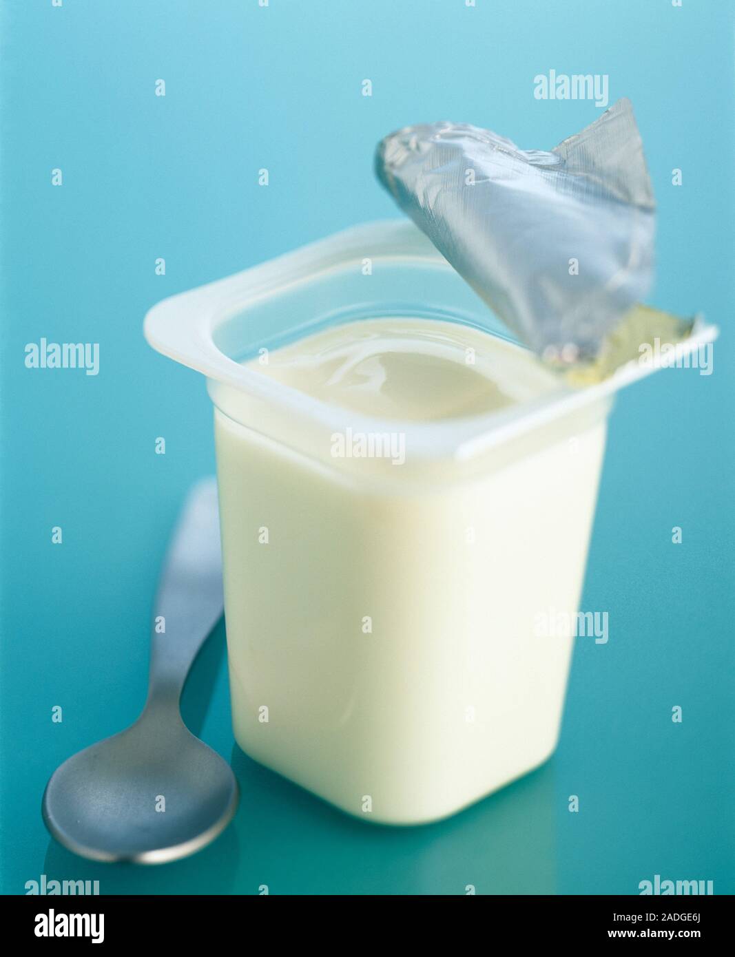 Yoghurt. Tub of yoghurt and a spoon. Yoghurt is a dairy product ...