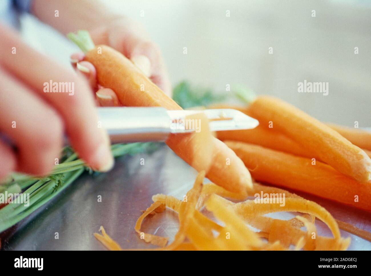Skinning a carrot using a potato peeler Stock Photo - Alamy