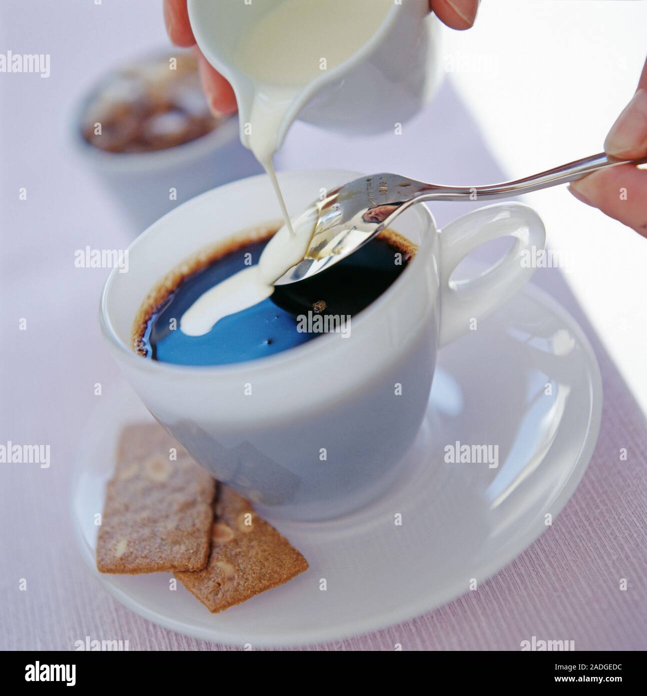 Adding cream to coffee over the back of a spoon Stock Photo - Alamy