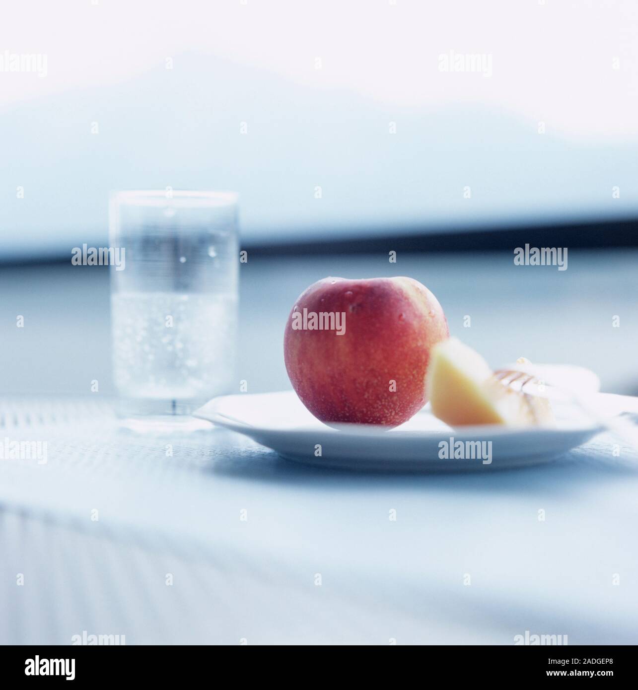 Nectarine (Prunus sp.) on a plate with cutlery. Nectarines are a type ...