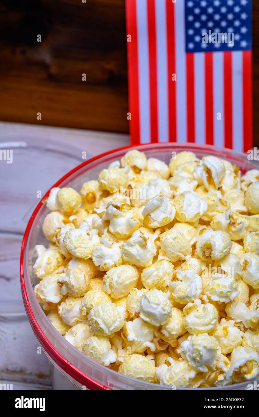Plastic bucket with tasty sweet popcorn ready to eat and flag of USA ...