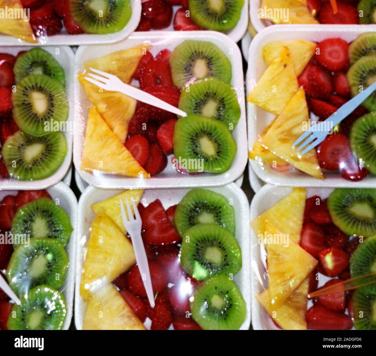 Fruit portions. Sliced pineapple, strawberries and kiwi fruit in trays ...