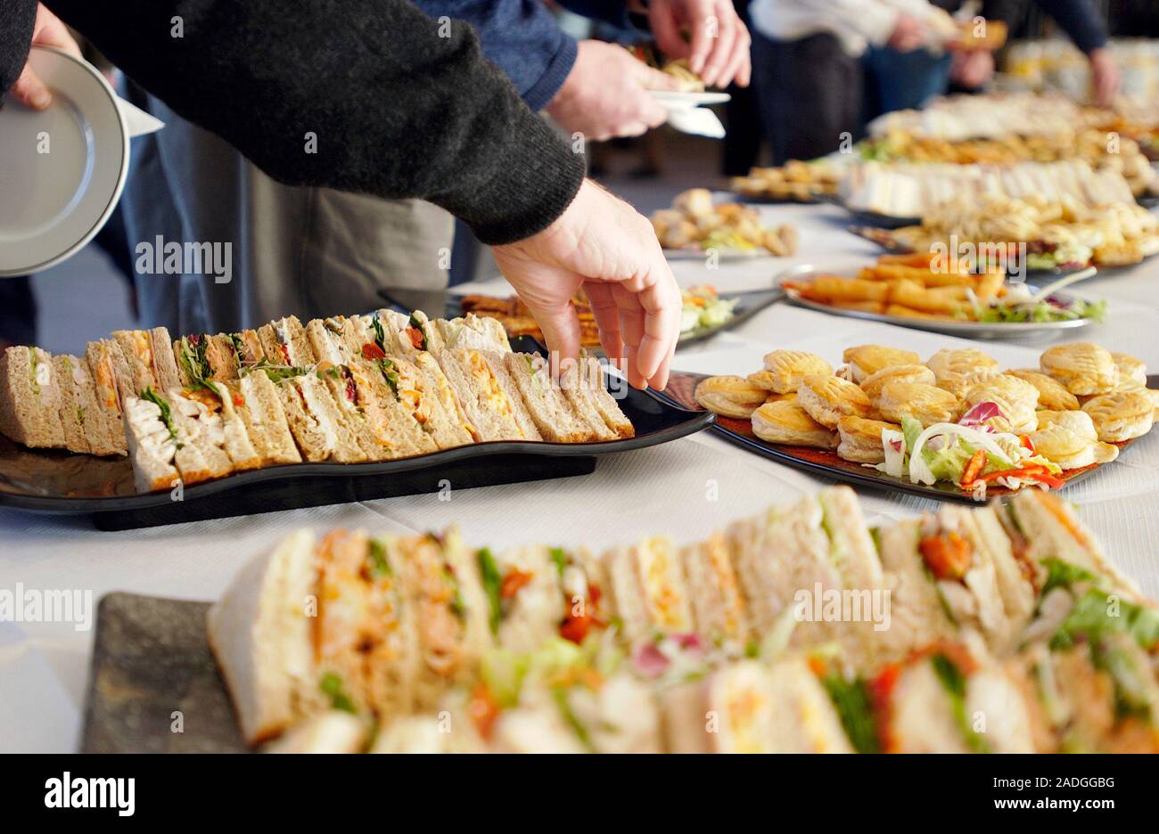 Buffet food. Man taking a sandwich from a platter at a buffet table ...