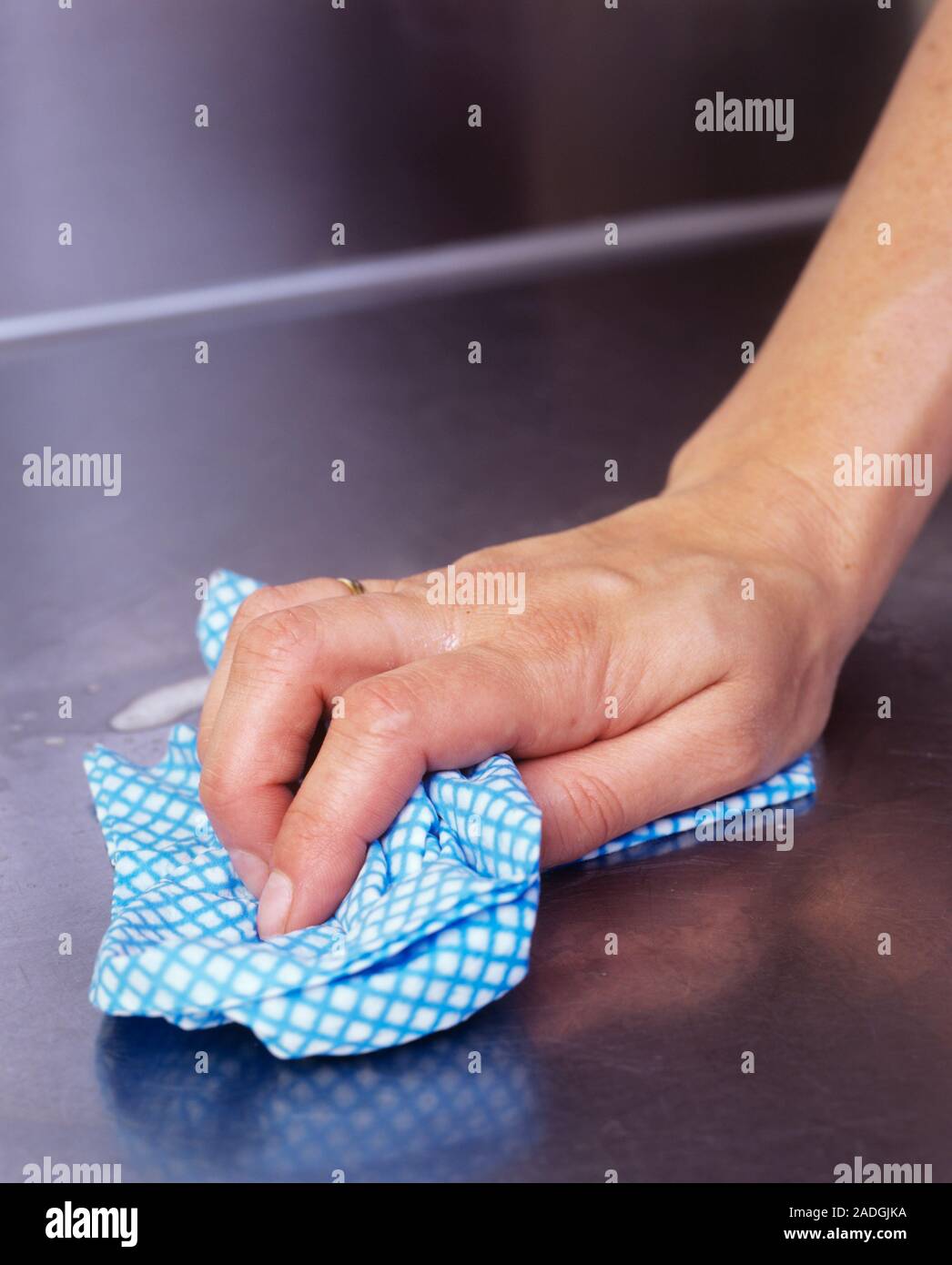 Wet cleaning cloth being used by a hand to clean a steel surface in a ...