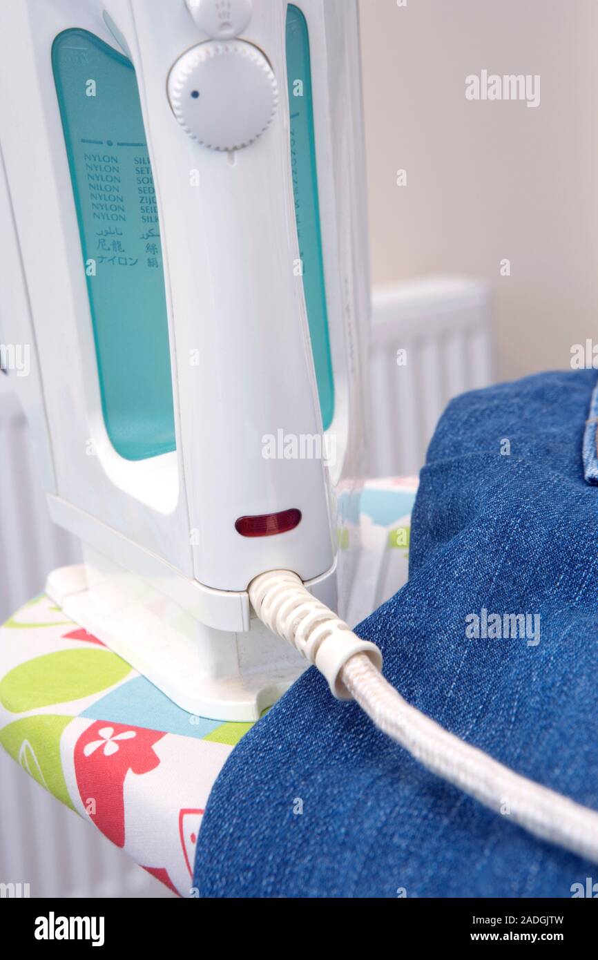 Iron standing upright on an ironing board Stock Photo - Alamy