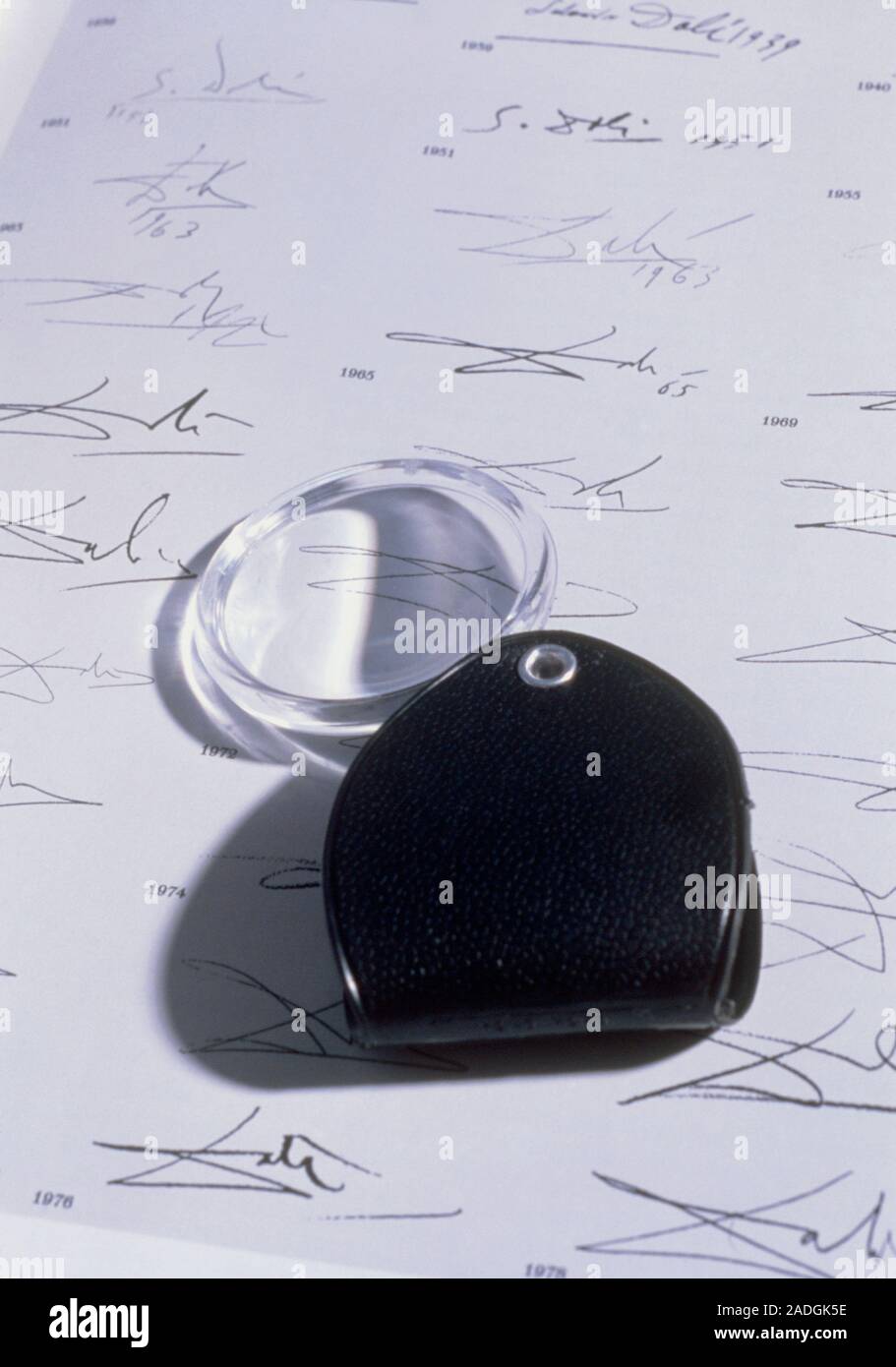 Art forgery detection. Magnifying glass on a sheet of authenticated ...