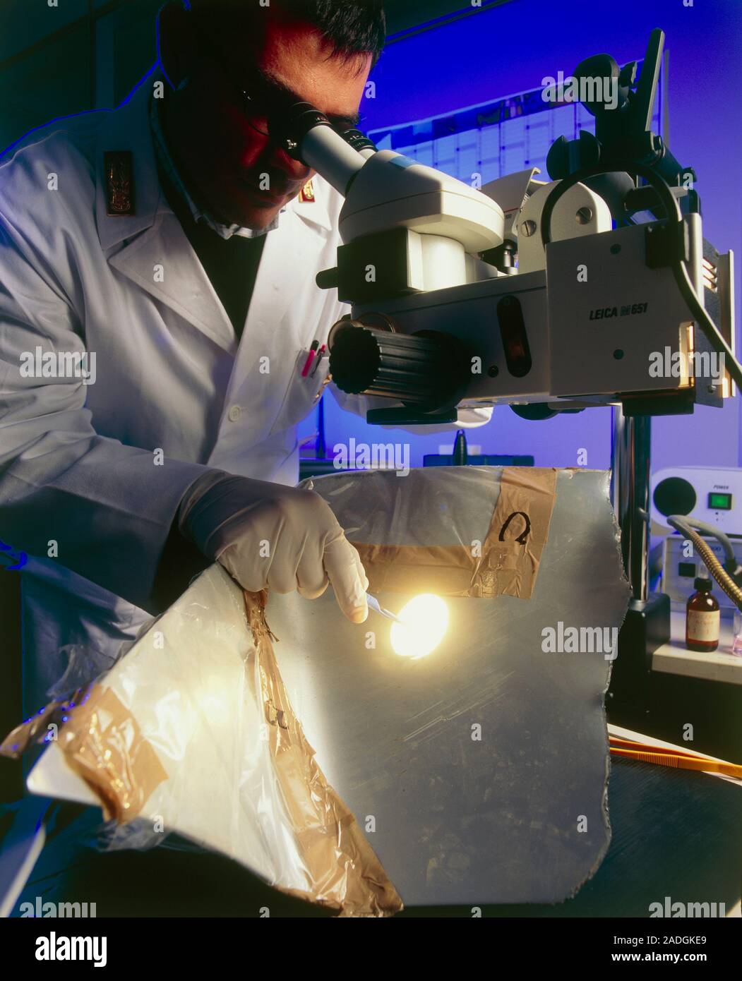 Collecting paint evidence. Forensic scientist collecting a paint sample ...