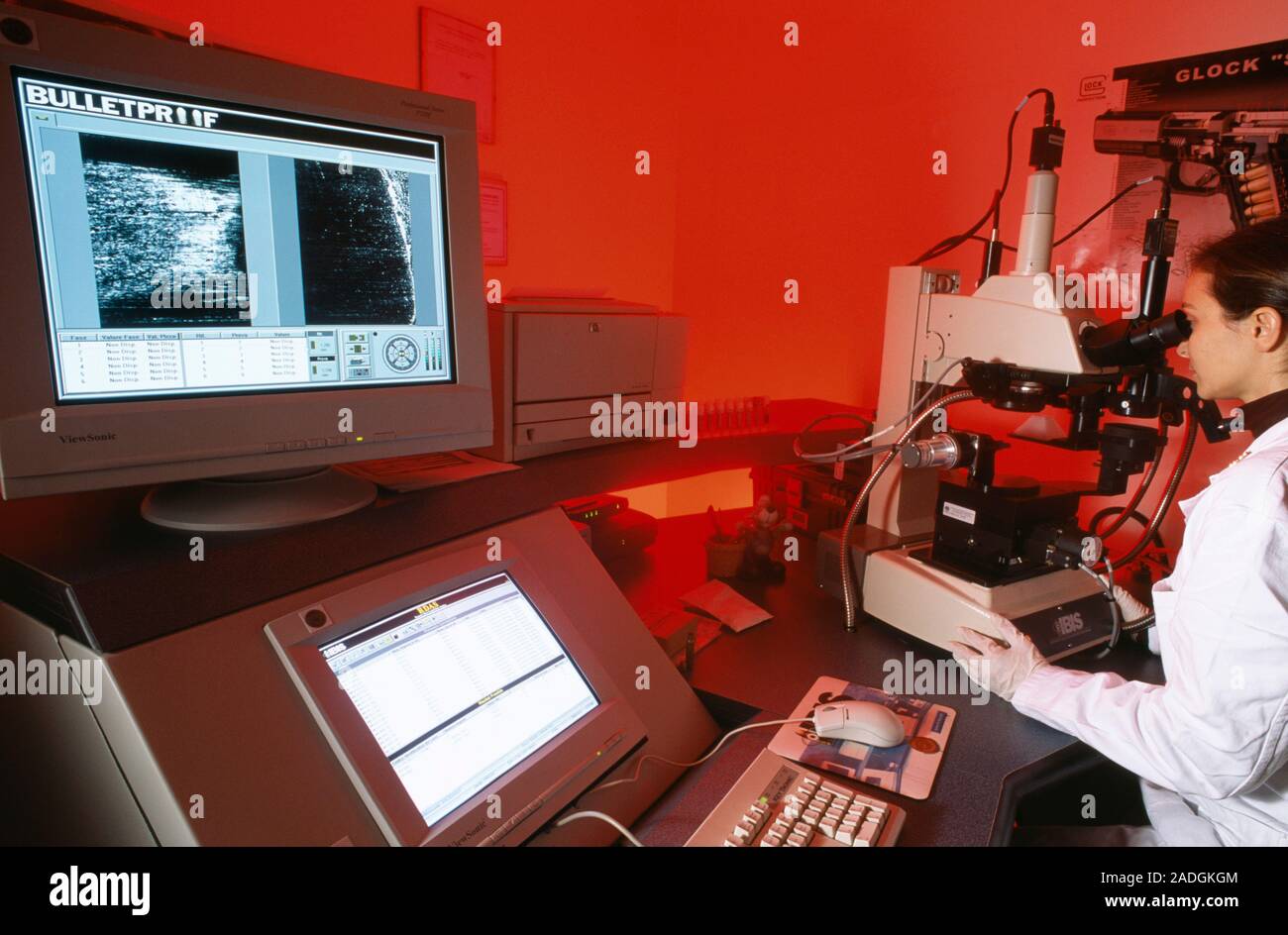 Comparing bullets. Forensic scientist using a microscope to compare ...