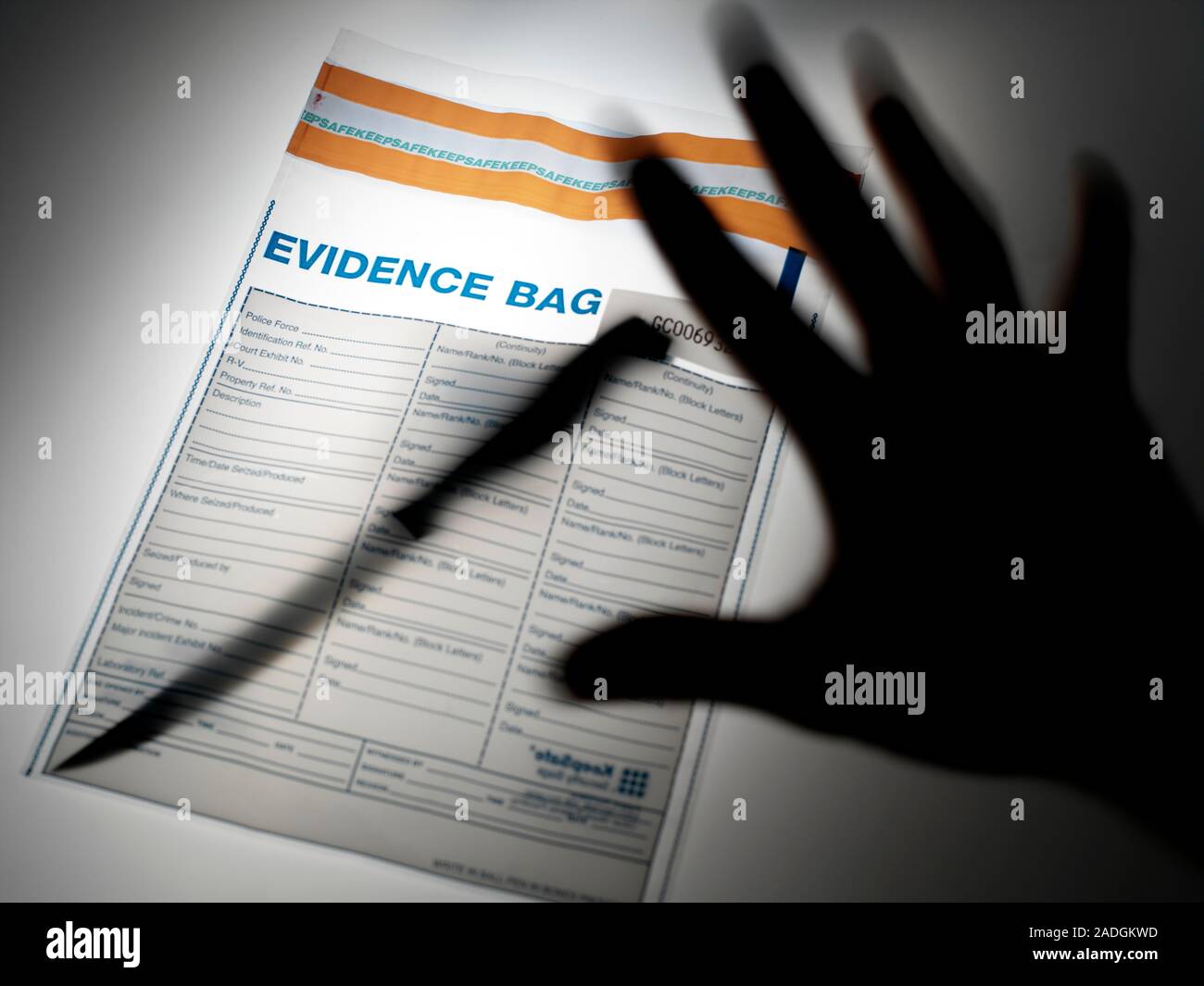 Forensic evidence. Silhouetted hand over an evidence bag containing a ...