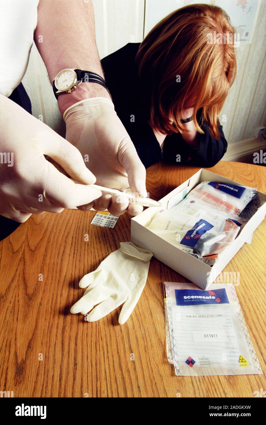DNA sampling. Policeman taking a DNA (deoxyribonucleic acid) sample ...
