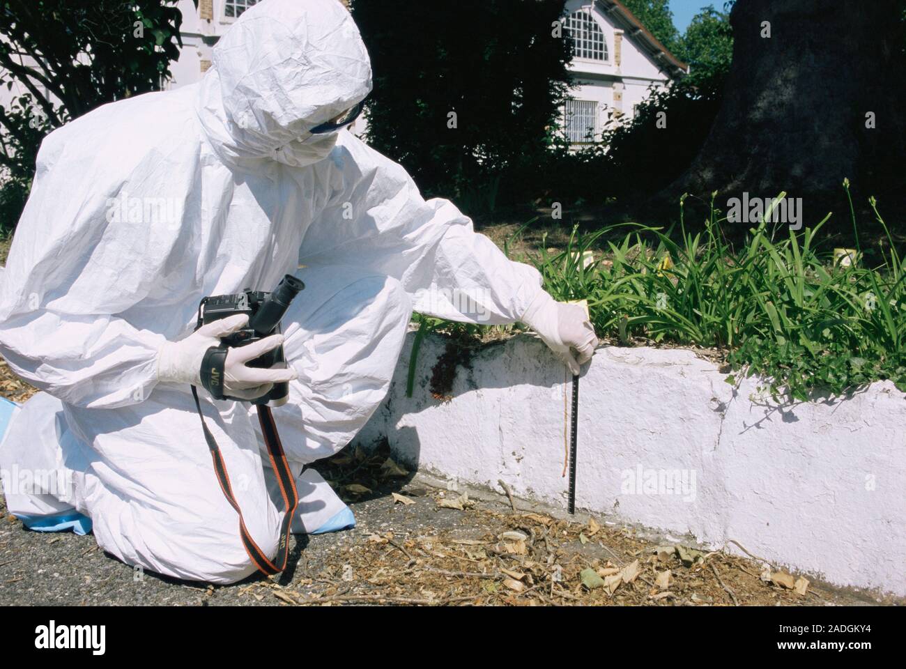 Forensics officer marking evidence at the scene of a crime. He is using ...