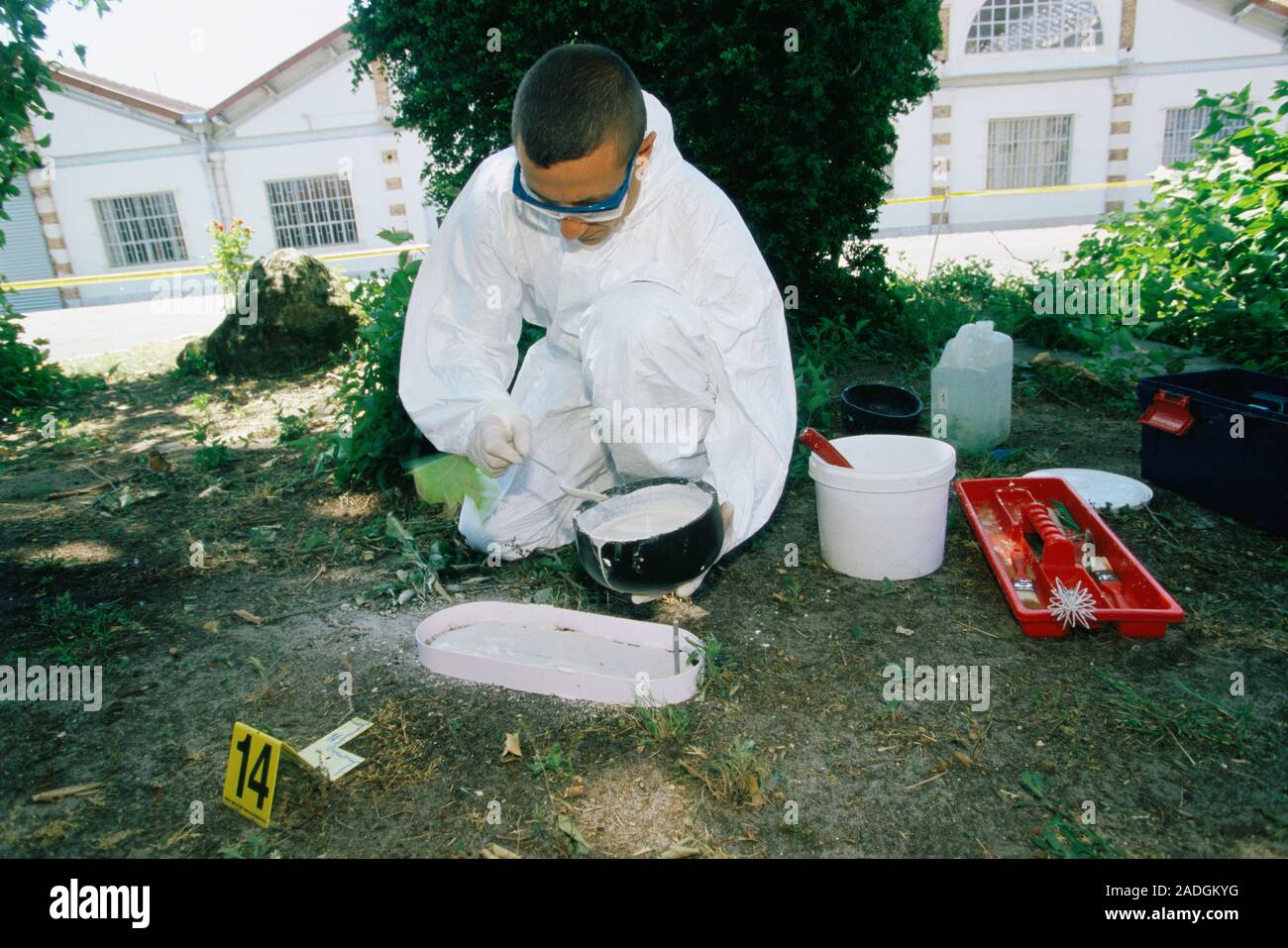 Forensics officer taking a cast of a footprint at the scene of a crime ...