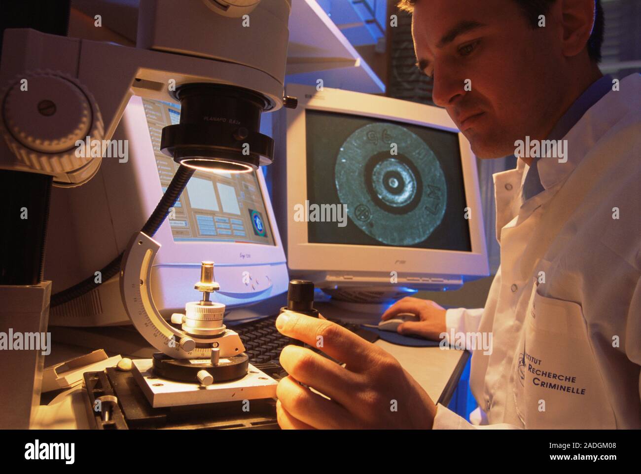 Forensic analysis of a bullet casing. Forensic scientist using a light ...