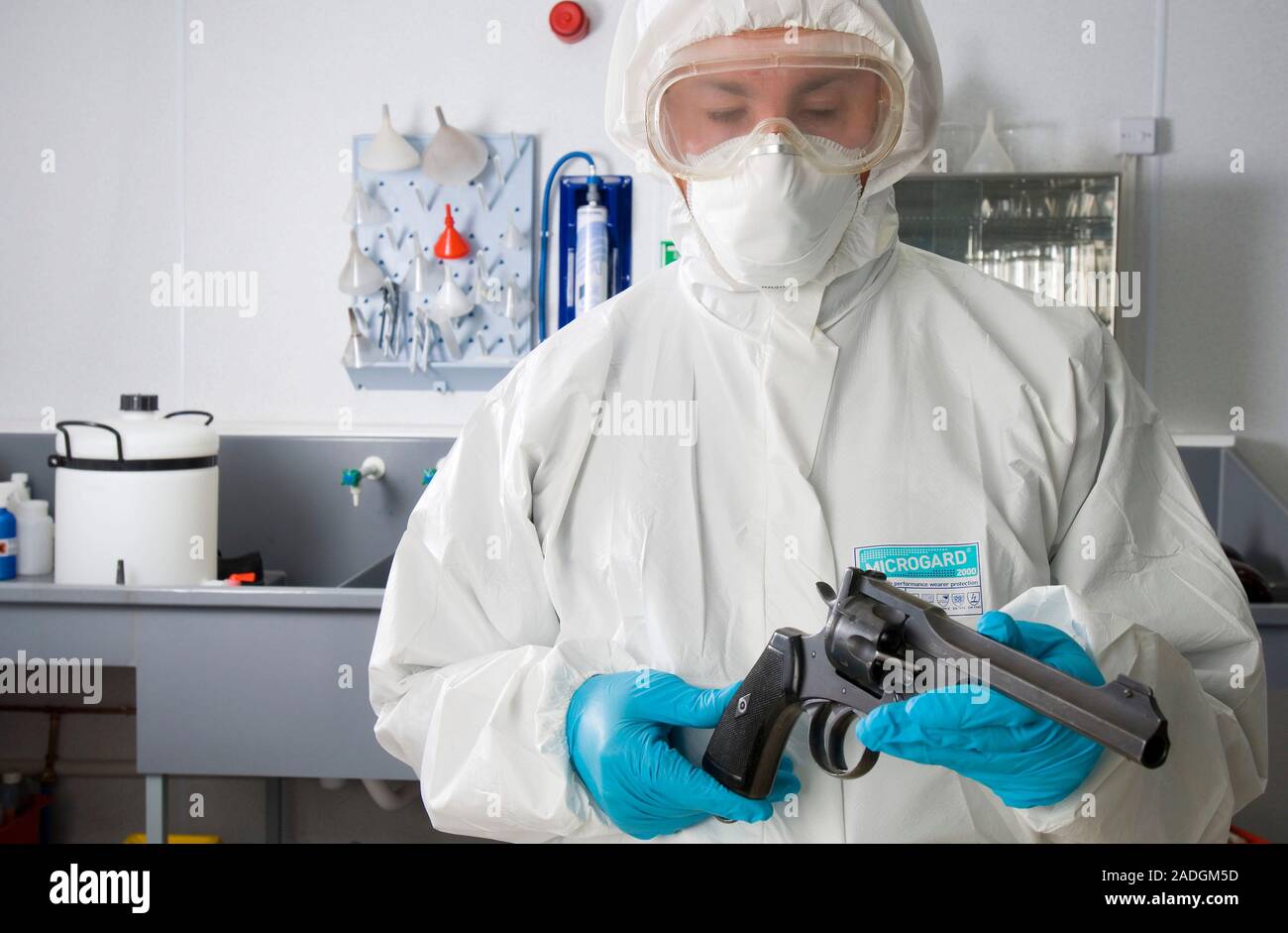 Forensics officer examining a handgun Stock Photo - Alamy