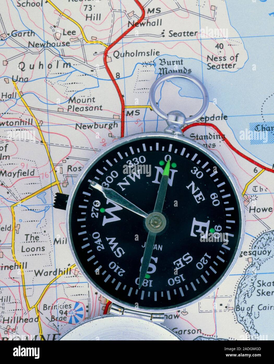 A magnetic compass resting on an Ordnance Survey map. The magnetic ...